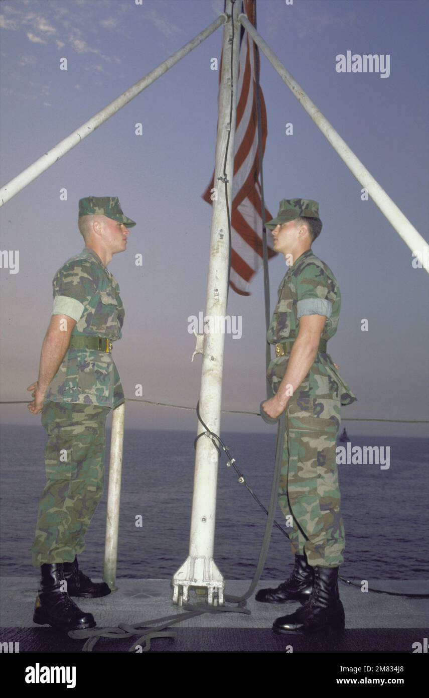 Marines lower the national ensign during evening colors aboard the ...