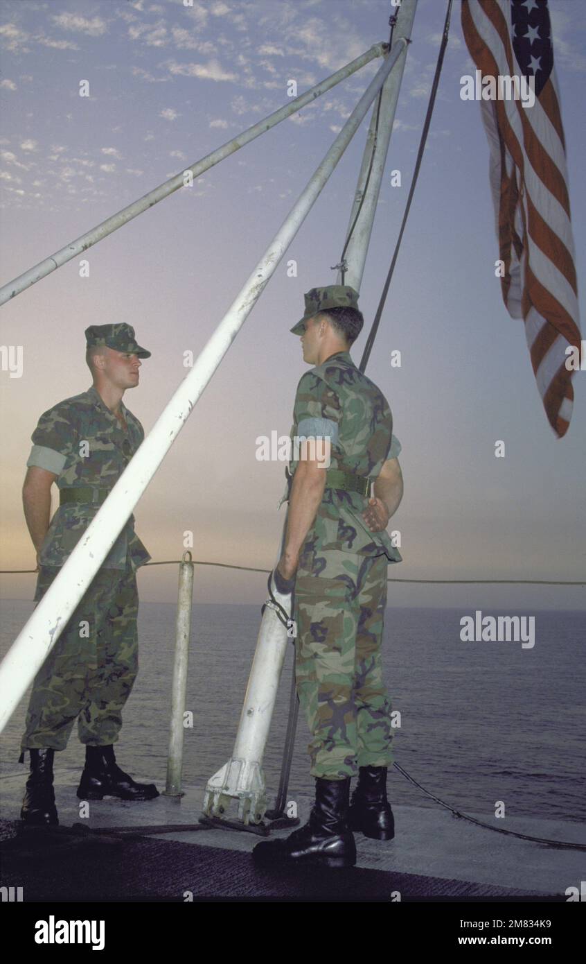 Marines lower the national ensign during evening colors aboard the ...