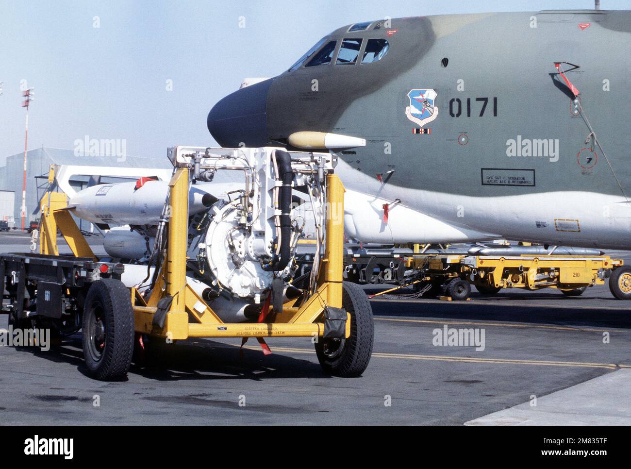 A weapons loader carrying a rotary rack launcher with inert training AGM-69A short range attack ...