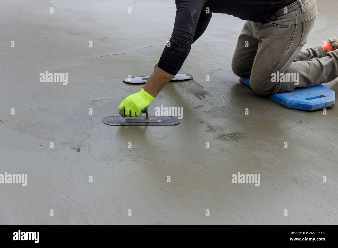 As masonry worker is holding steel trowel in his hand, he smoothing plastering concrete to ...