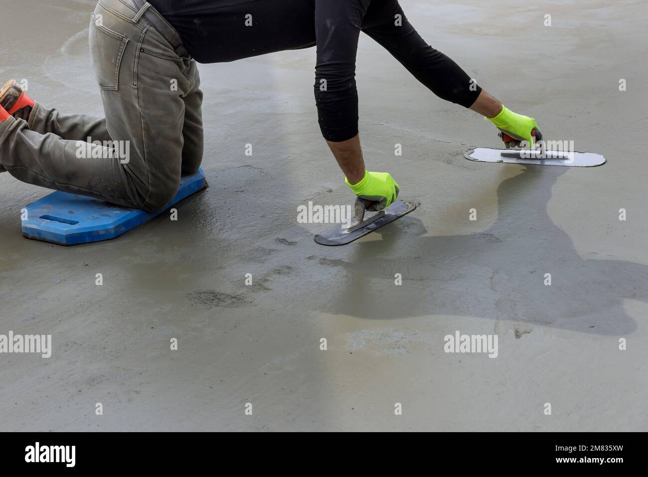 As he holds steel masonry trowel in his hand masonry worker smooths ...