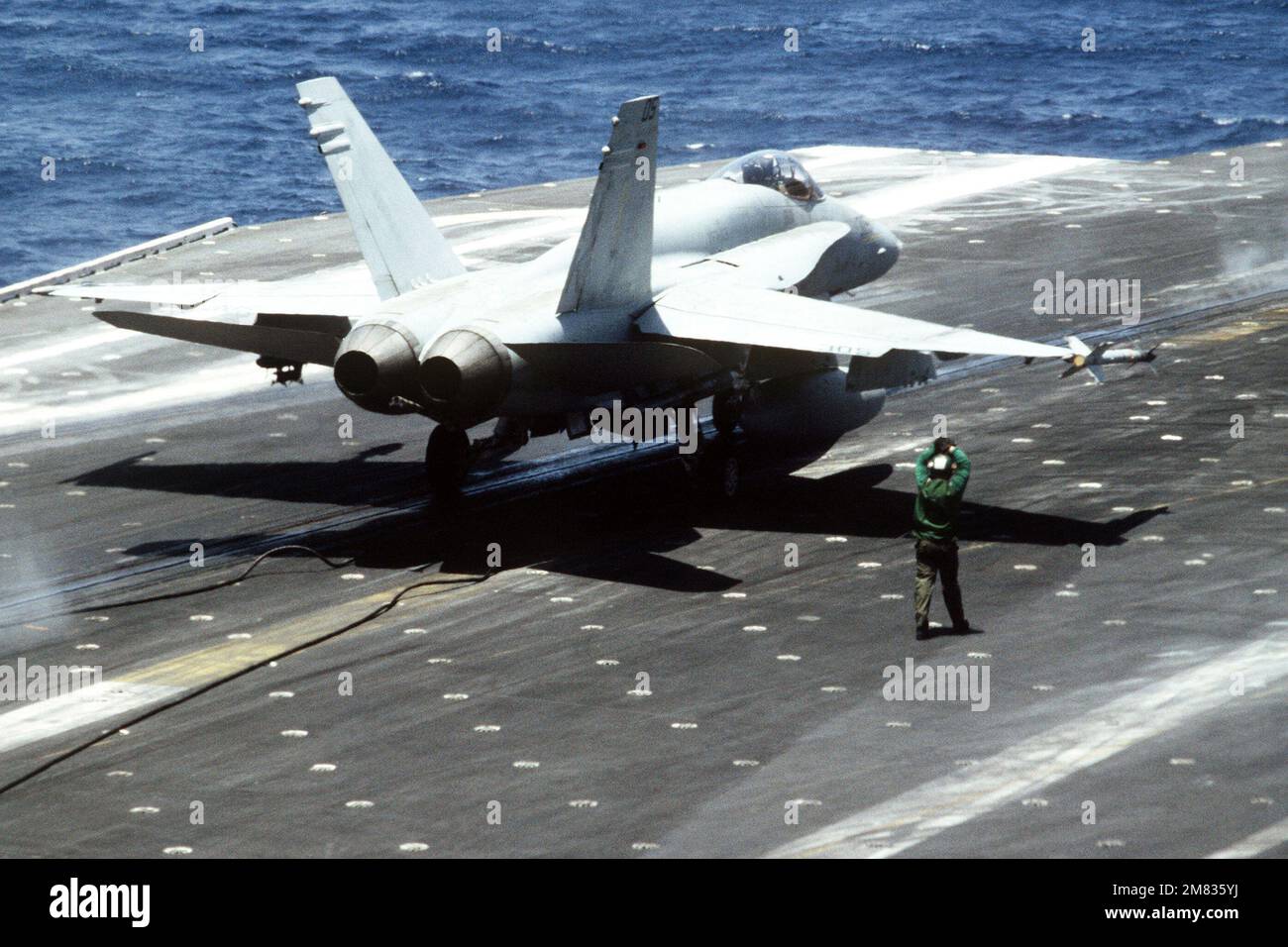 A hook releaseman signals downlock instructions after the arresting ...