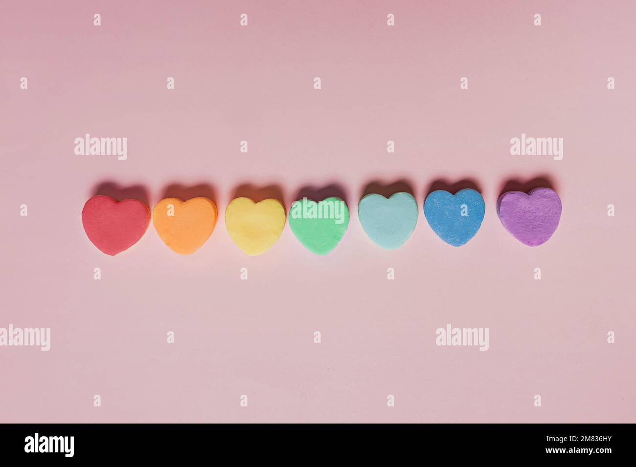 Rainbow colored heart shaped candies on pink background, Valentine's ...