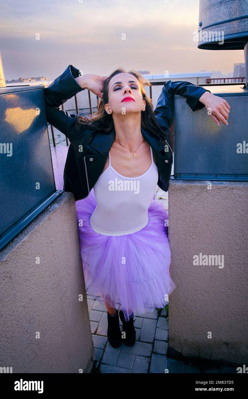 a ballerina in a tutu stands between the supports on the roof, leaning on her hands and throwing ...