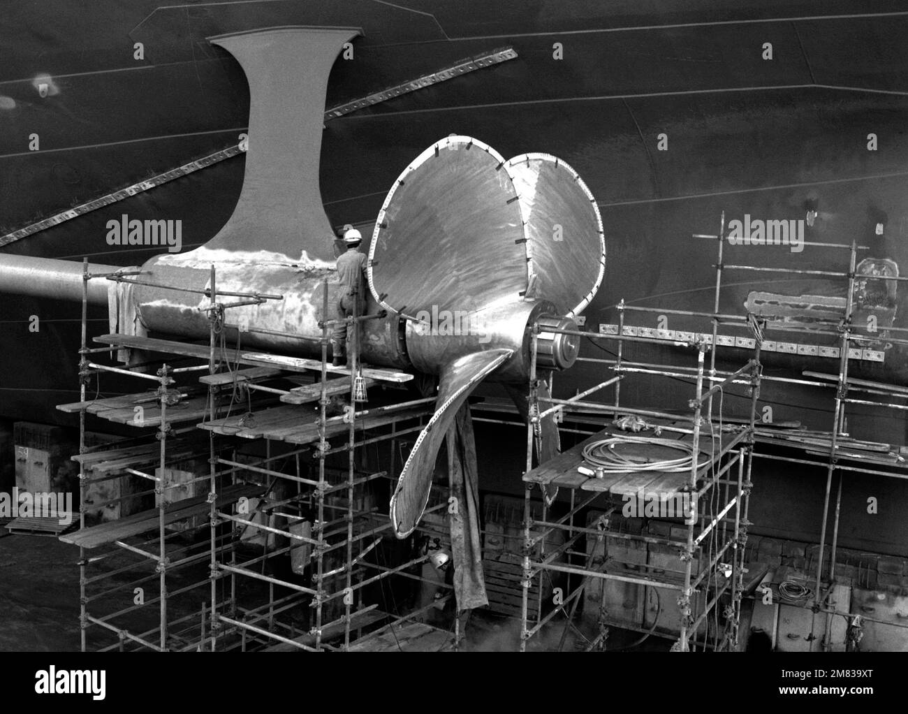 A worker prepares the No. 4 propeller for removal from the battleship ...