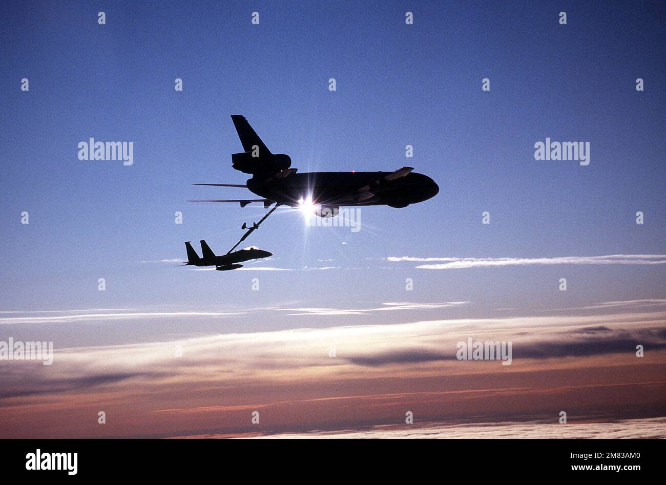 An air-to-air right side silhouetted view of an F-15 Eagle aircraft ...