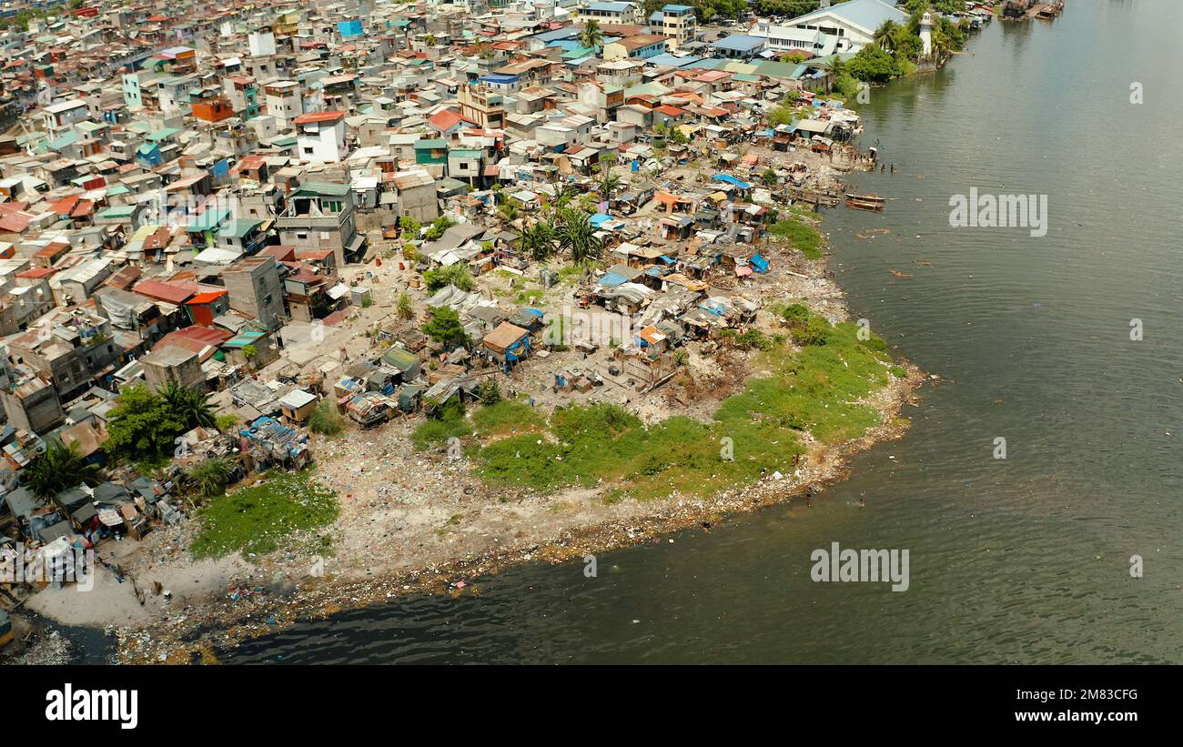 Slums near the port in Manila on the bank of a river polluted with ...