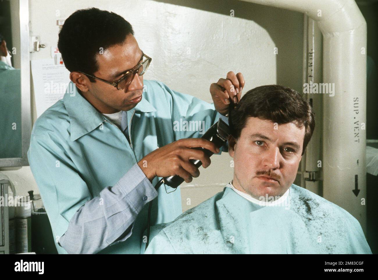 A crewman aboard the battleship USS IOWA (BB 61) gets a haircut in the ...