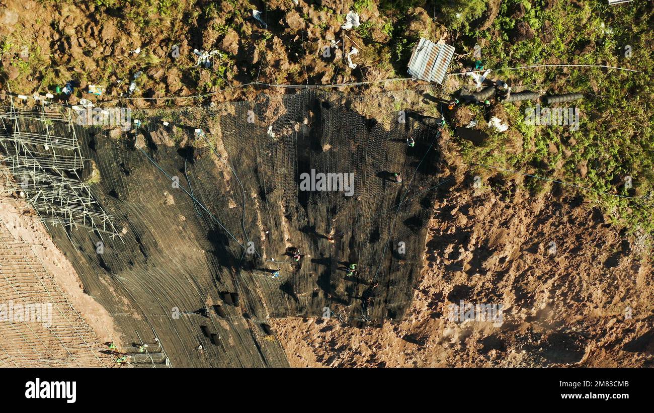 Workers strengthen the slope of the mountain with metal mesh preventing ...