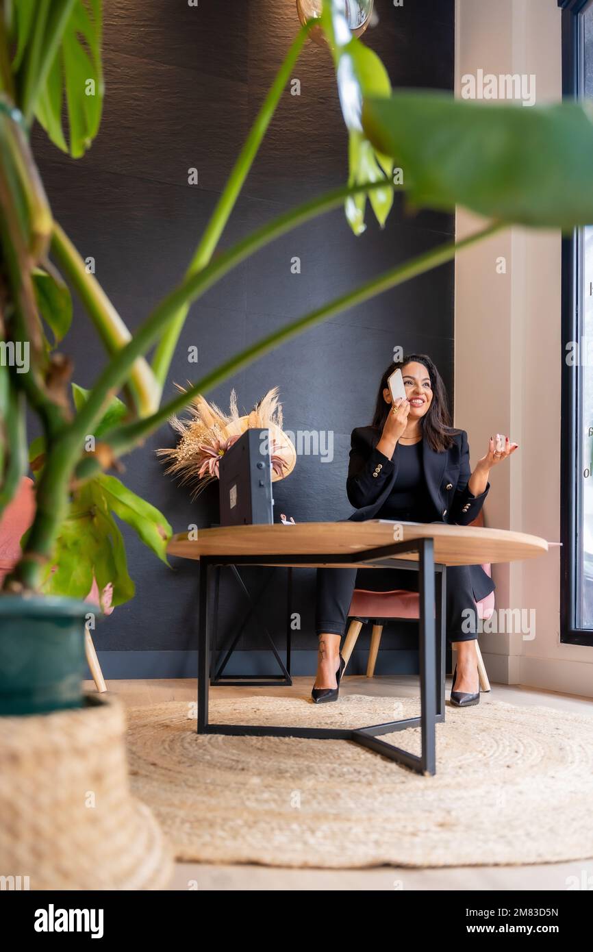 A Latin woman sitting and talking with phone aesthetic store of ...