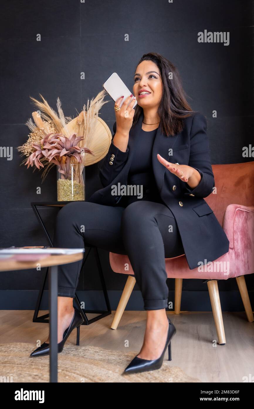 A Latin woman sitting and talking with phone aesthetic store of ...