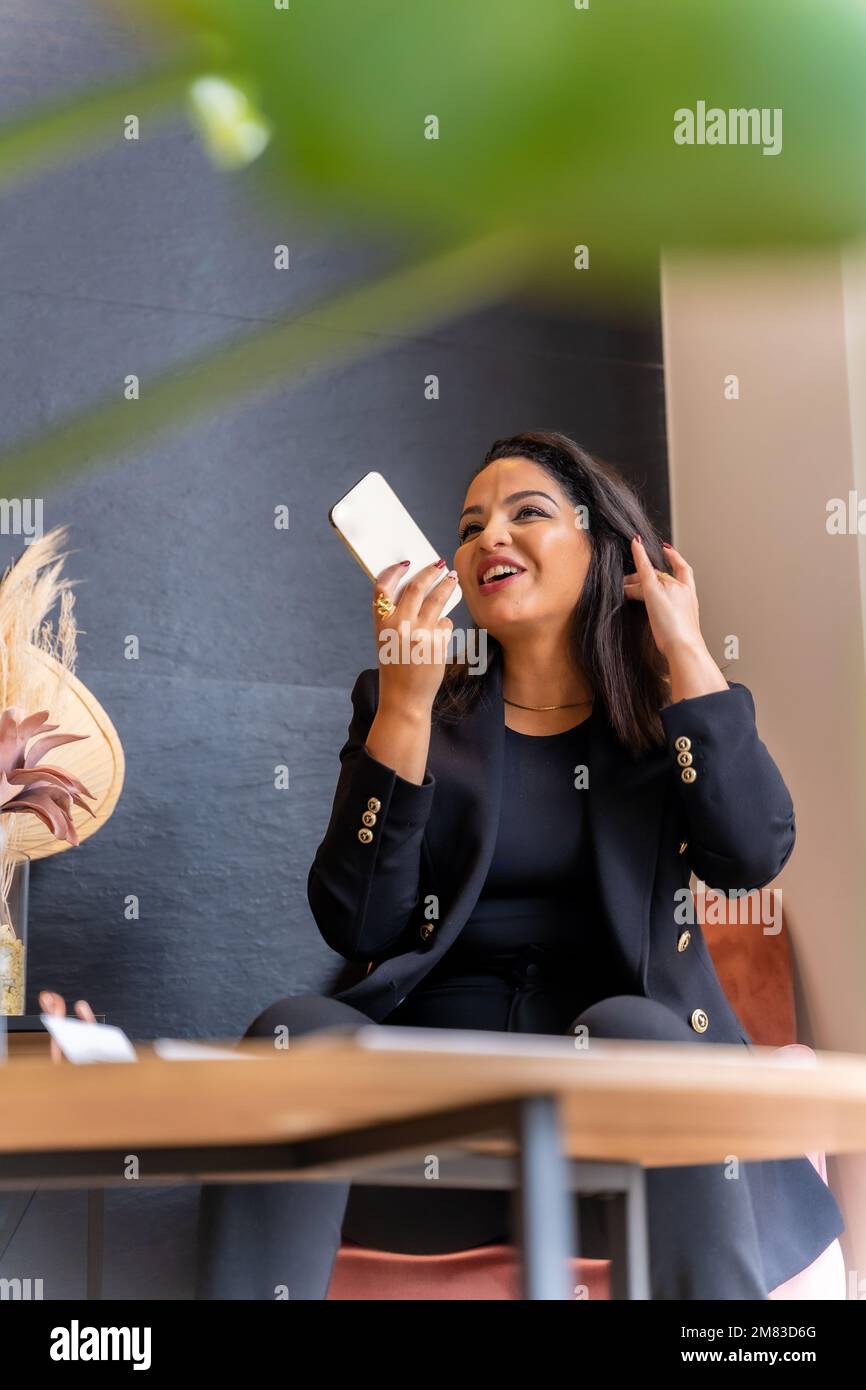 A Latin woman sitting and talking with phone aesthetic store of ...