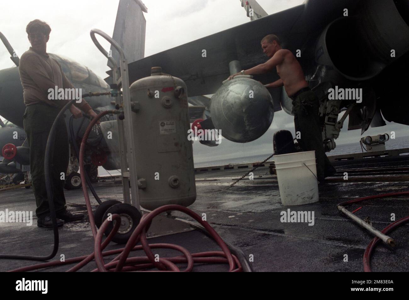 AIRMAN Rundquist and PETTY Officer Third Class Shaw wash an F/A-18 ...