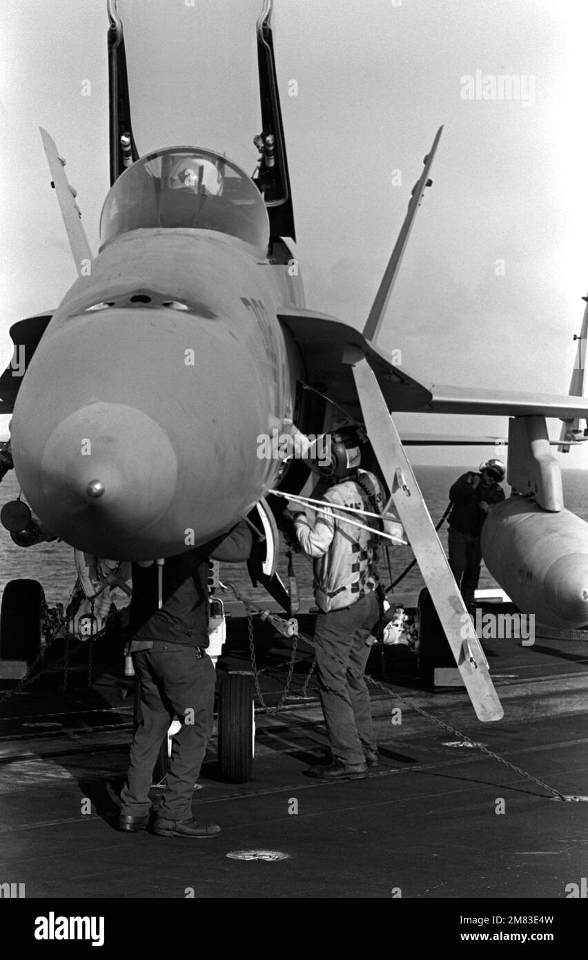An F/A-18 Hornet aircraft is examined by a member of Strike-Fighter ...