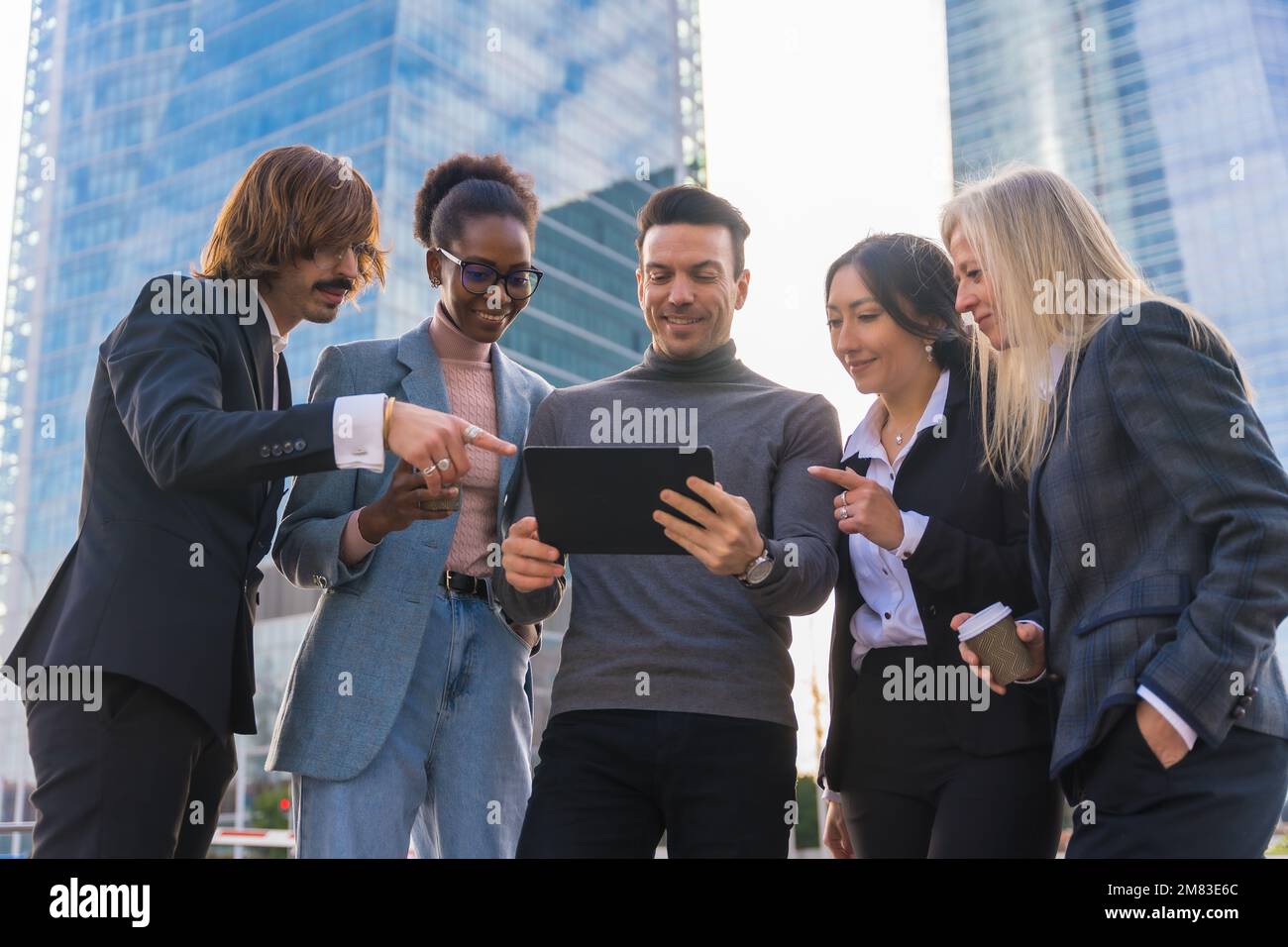 A group of multi-ethnic people in a business park looking at a tablet ...