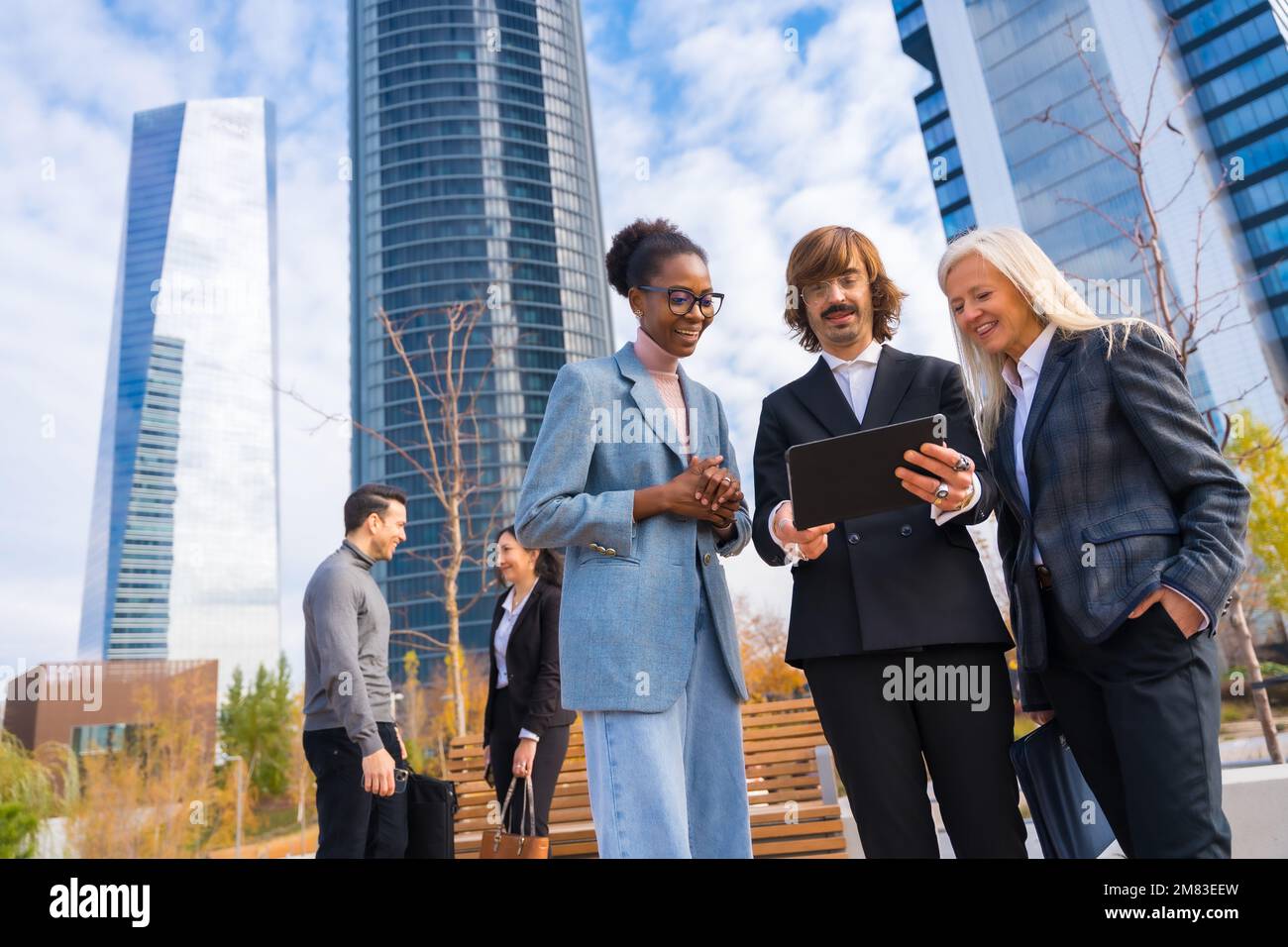 A group of multi-ethnic people in a business park looking at a tablet ...