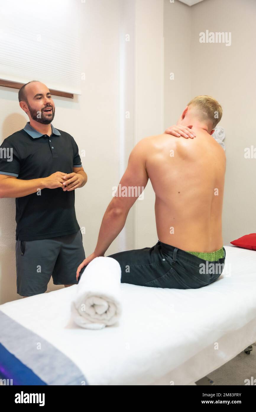 A vertical shot of a client explaining back and neck pain to the ...