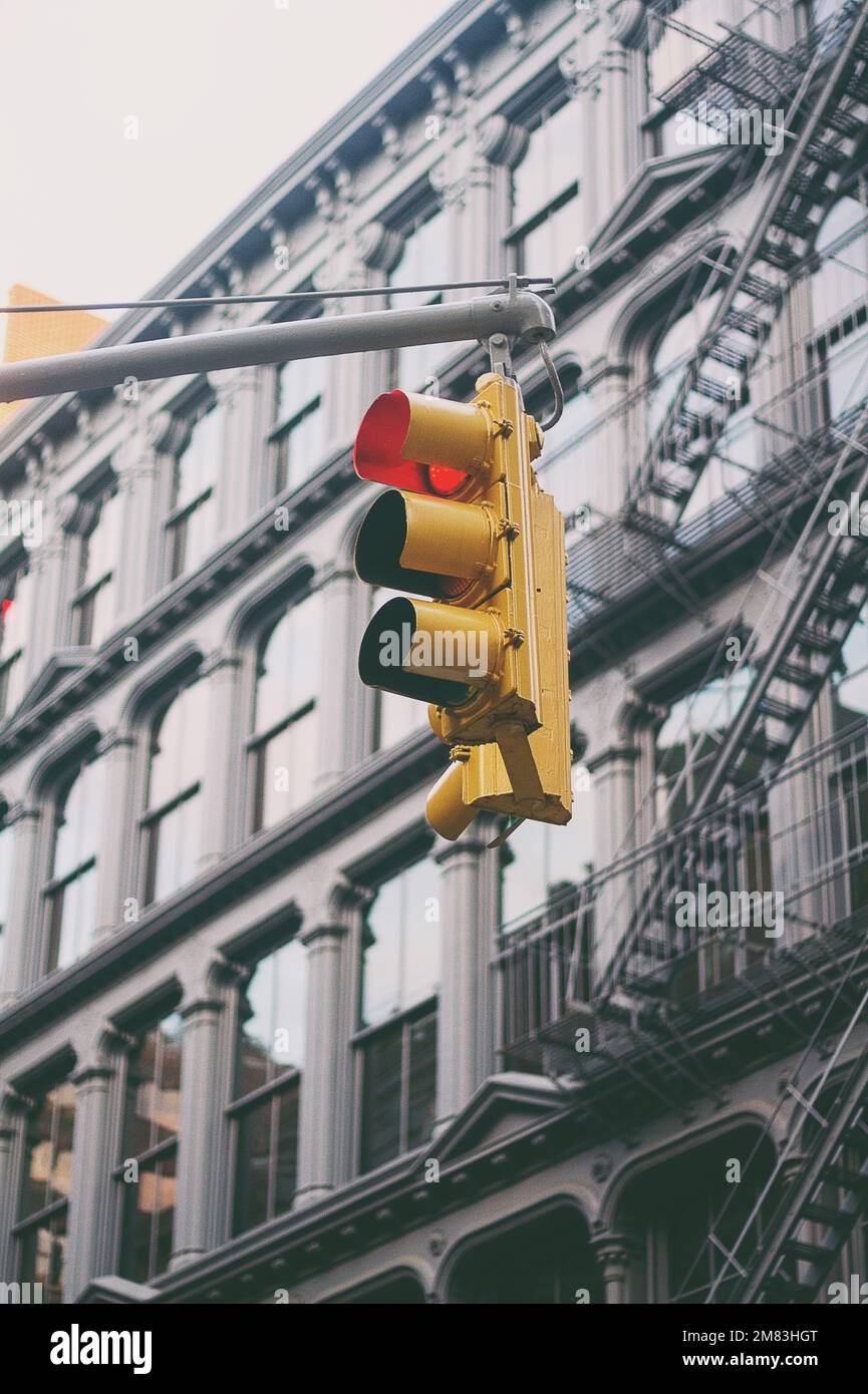 A vertical shot of hanging traffic lights with the red light on and a ...