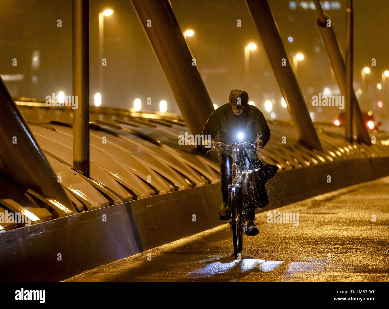 UTRECHT - A cyclist braves the strong wind and rain on the Prince Claus ...