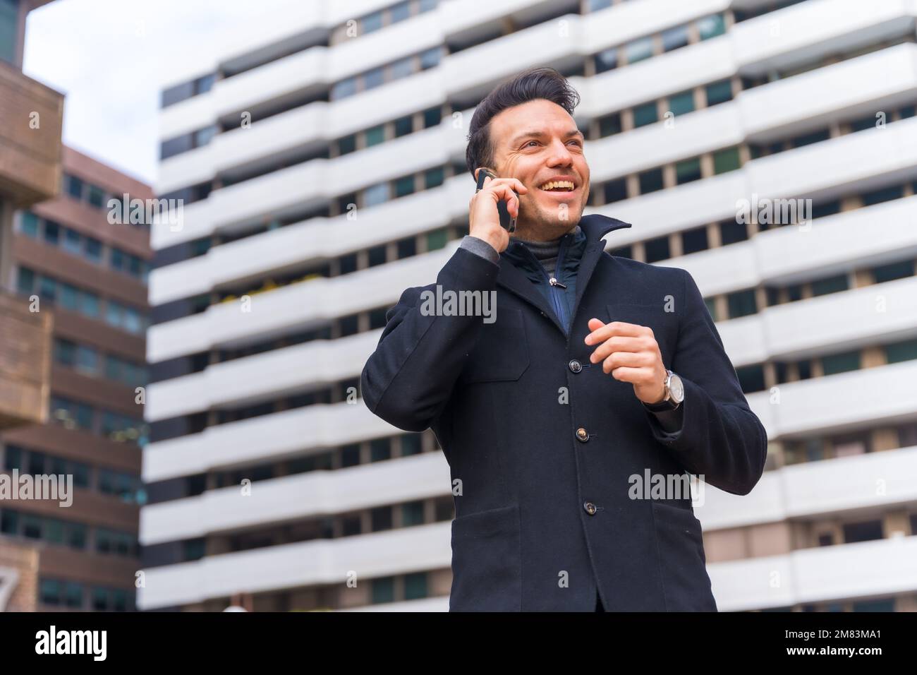A middle-aged Caucasian businessman smiling and talking on the phone in ...