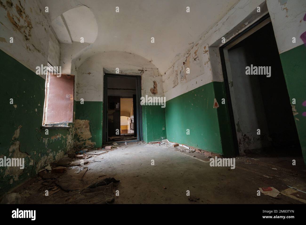 Sunlit hallway with opened doors and window on weathered walls inside ...