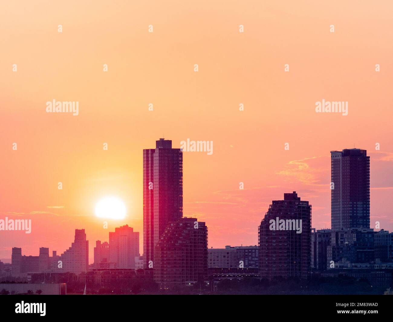 The bright sun setting in orange sky above Jersey City skyline in the ...