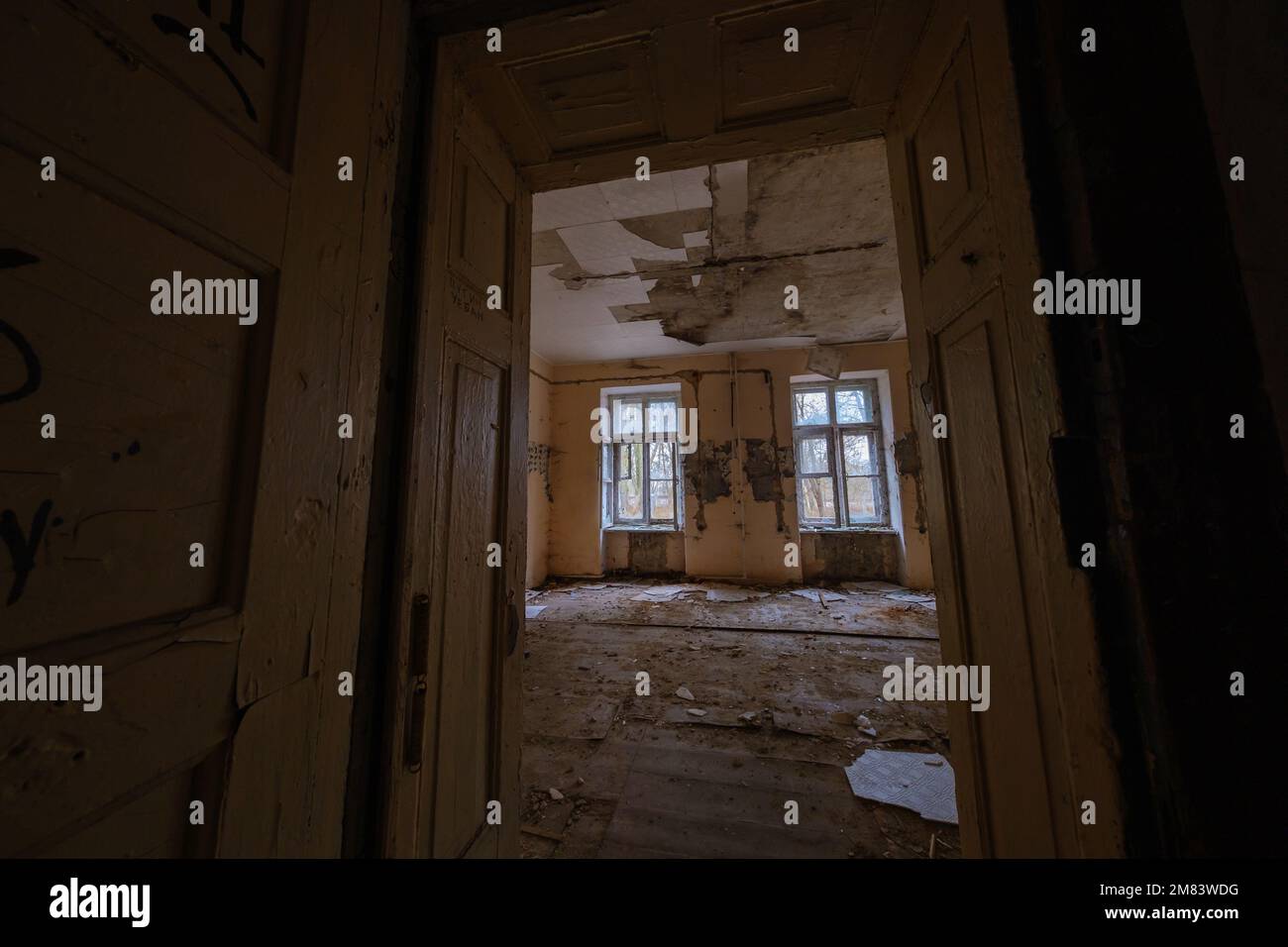 Weathered room with pair of windows located behind opened door inside ...