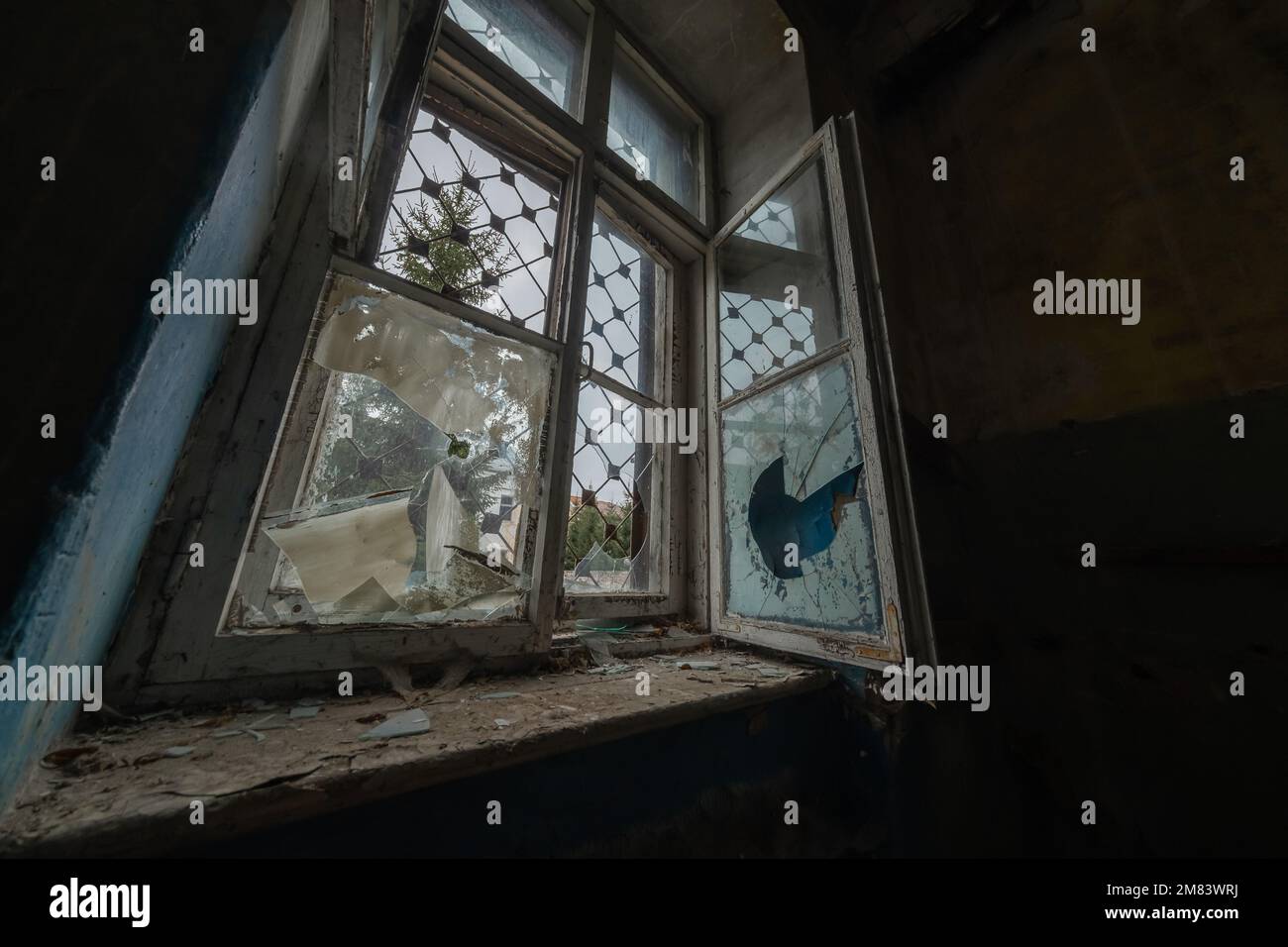 Opened window with shattered glass inside dark room of abandoned ...