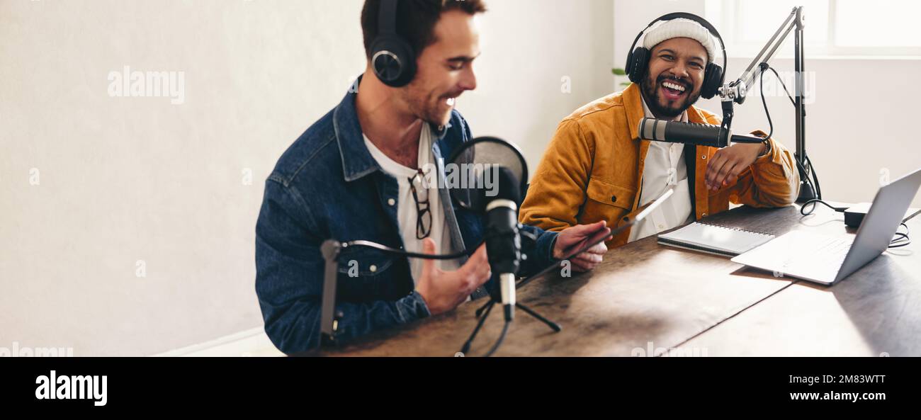 Cheerful podcasters laughing and having a good time in a home studio ...