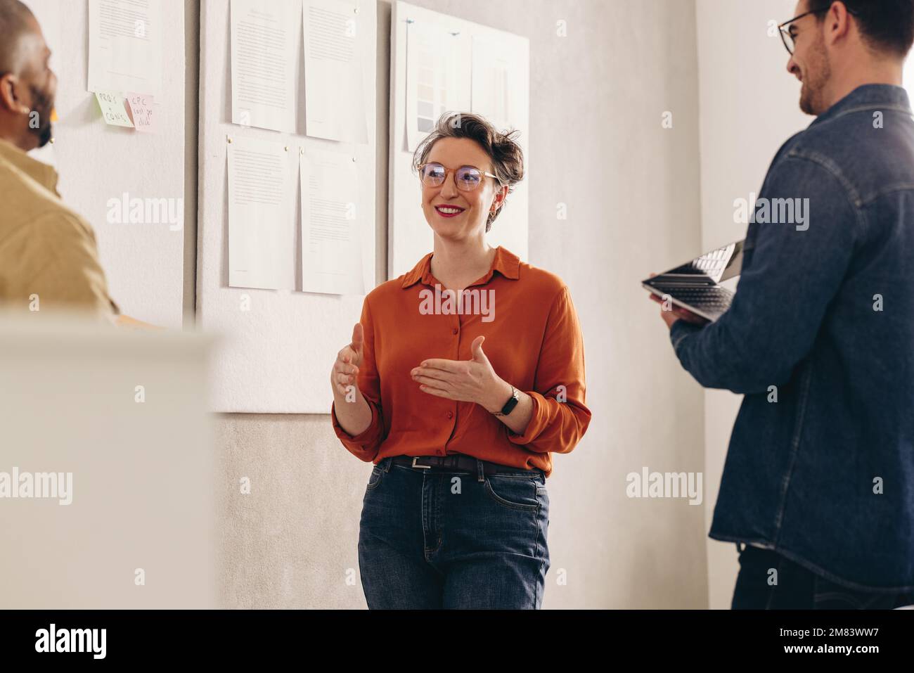 Happy businesswoman having a discussion with her team next to some ...