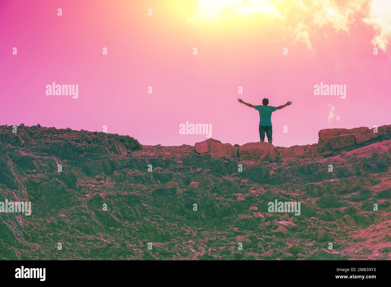 A man with hands in the air standing on the cliff in the desert Stock ...