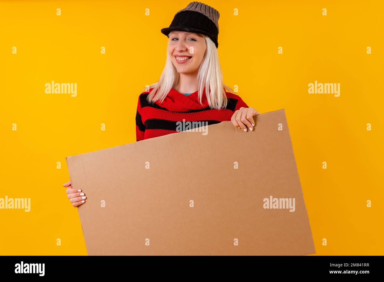 A blonde Caucasian woman holding a cardboard advertisement poster with ...