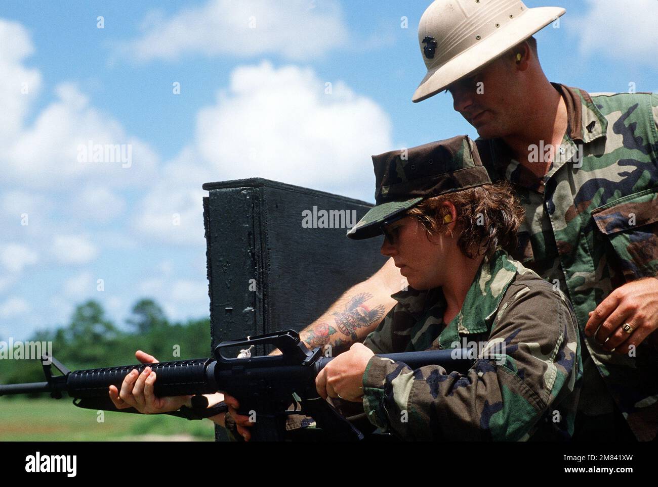 A drill instructor shows a woman Marine recruit how to handle an M-16A2 ...