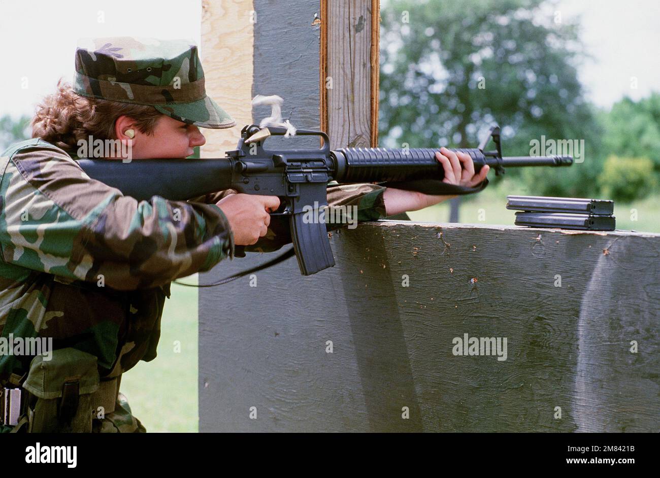 A woman Marine recruit fires an M-16A2 rifle from a standing position ...