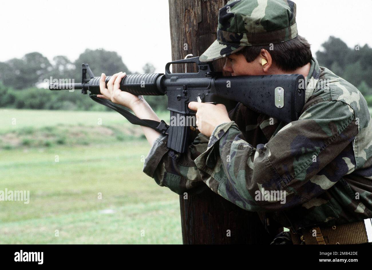 A woman Marine recruit fires an M-16A2 rifle from a standing position ...