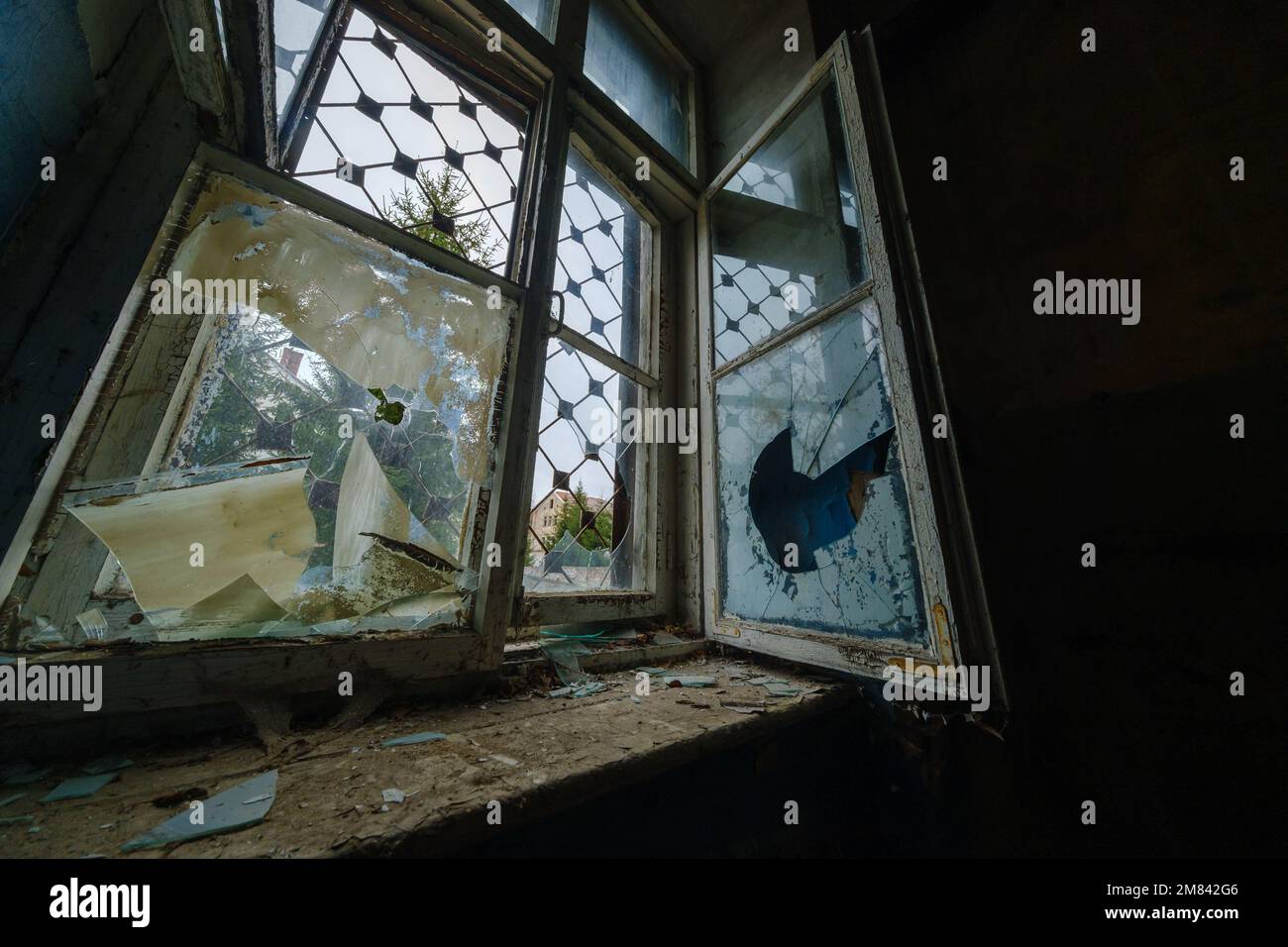 Opened window with shattered glass inside dark room of abandoned ...
