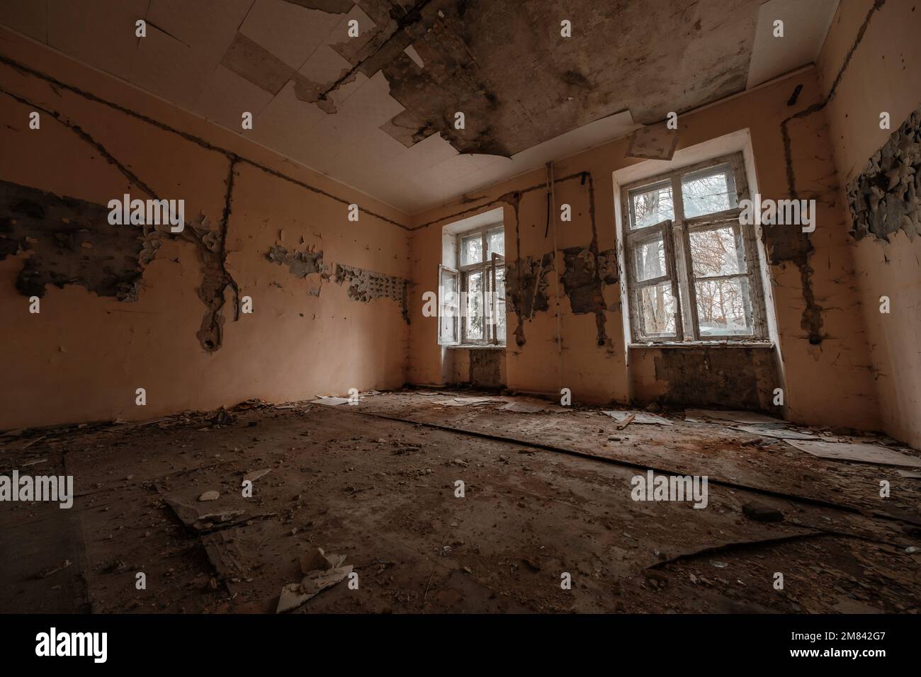 Weathered room with pair of windows located behind opened door inside ...