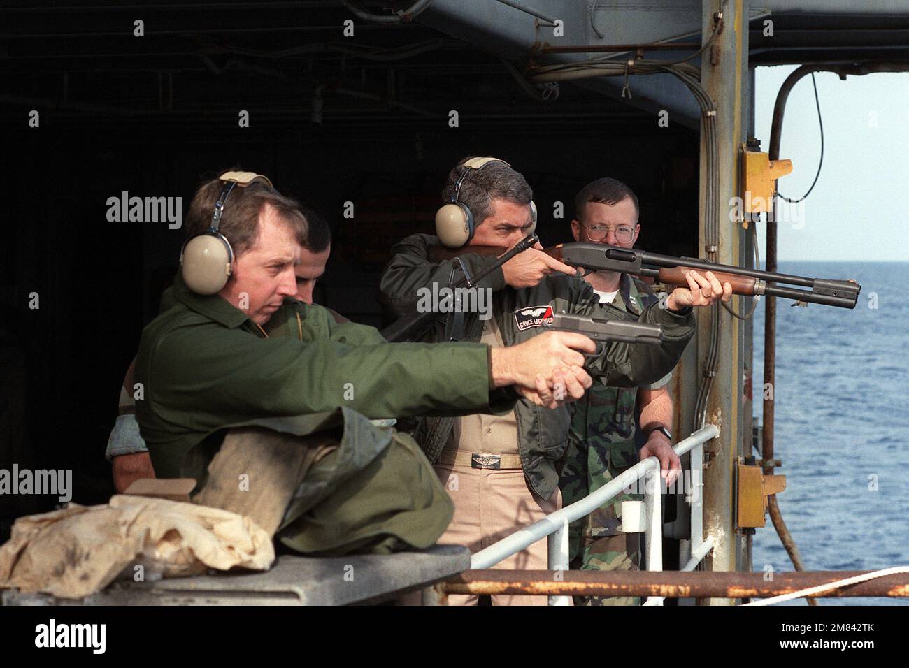 A pilot fires a 12-gauge pump shotgun as another crewman fires an M ...