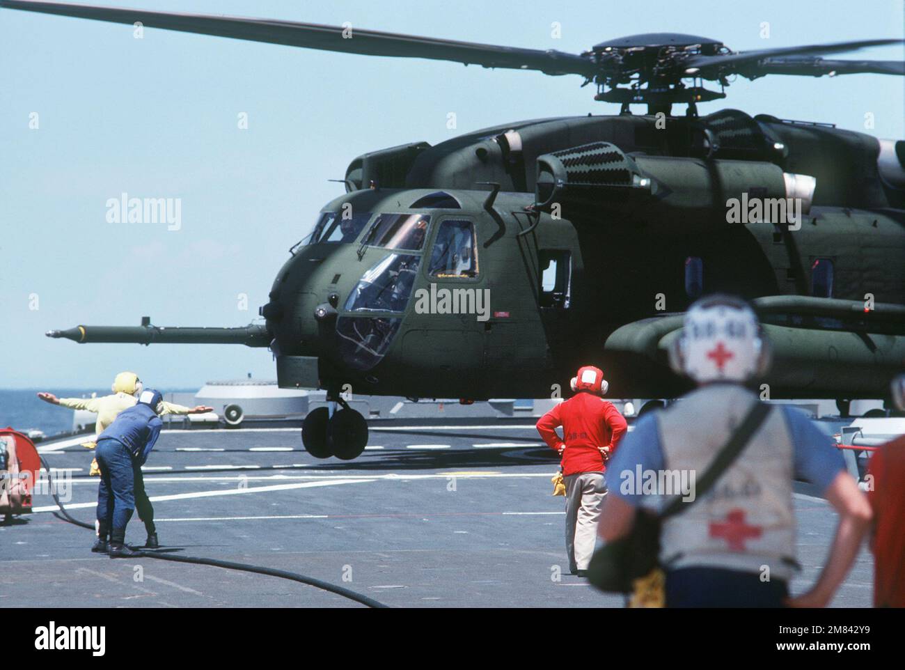A landing director signals instructions to the pilot of a CH-53E Super ...