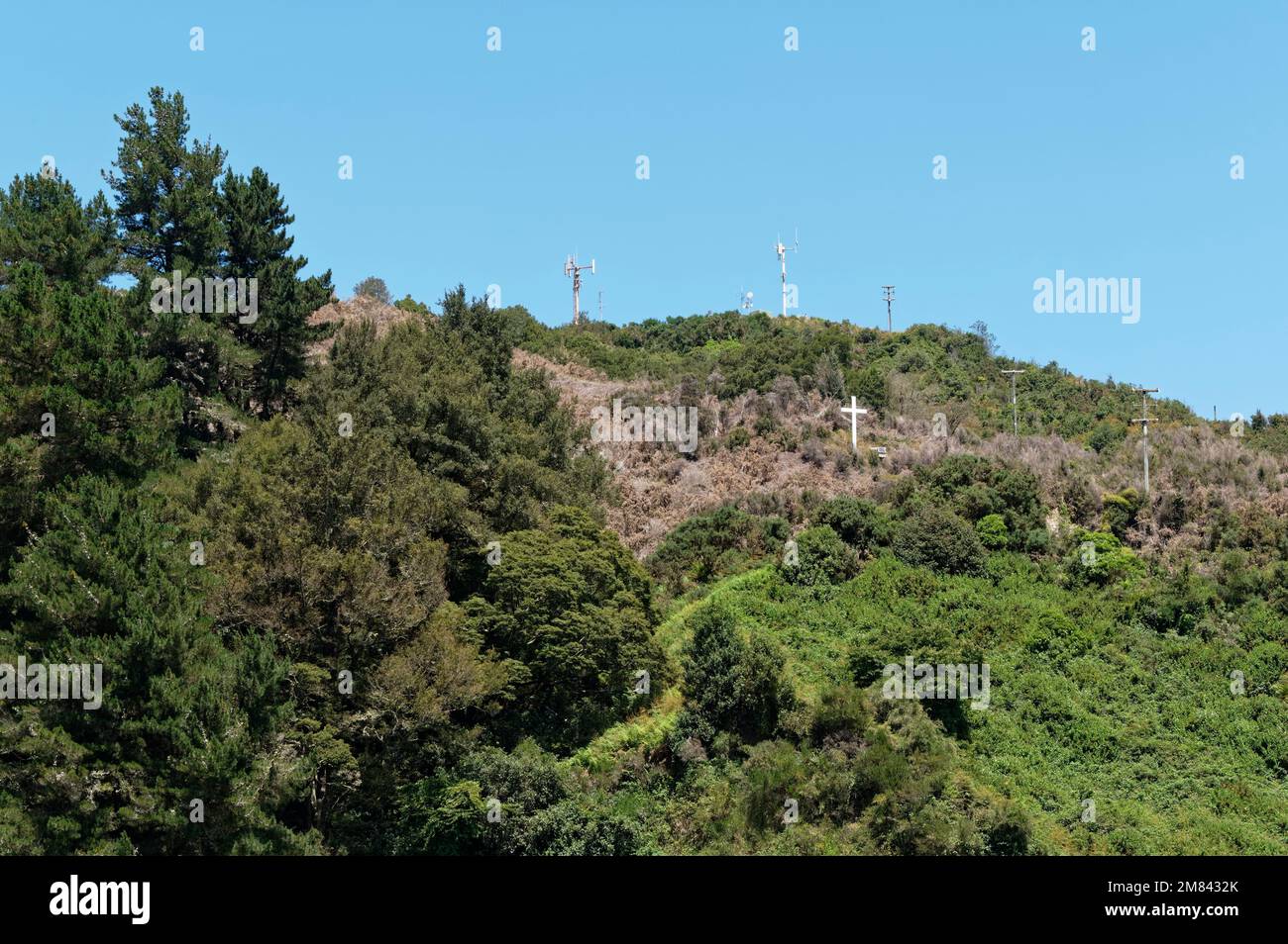 A white cross sits amongst communication aerials on the hill opposite ...
