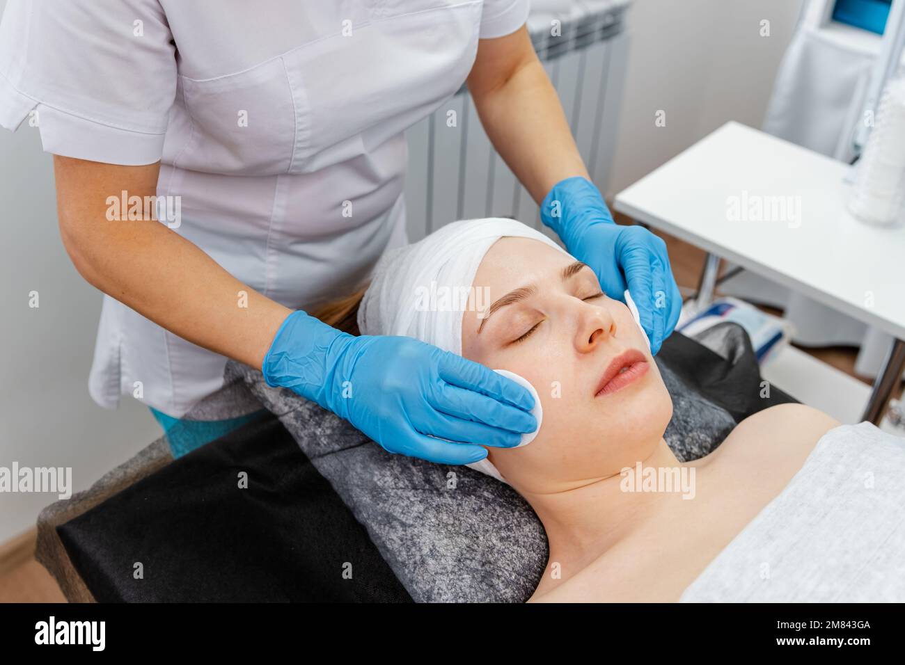 Hands of skillful beautician cleaning female face with cotton pad Stock ...
