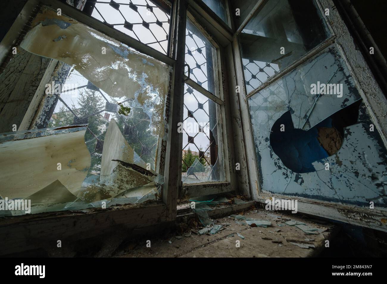 Opened window with shattered glass inside dark room of abandoned ...