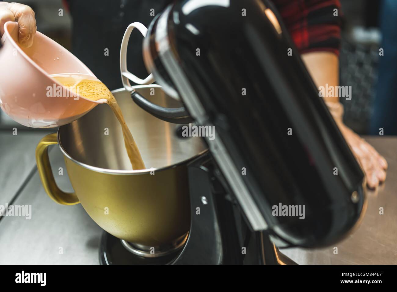 putting ingredients in a modern kitchen stand mixer to bake cakes, dessert concept. High quality ...