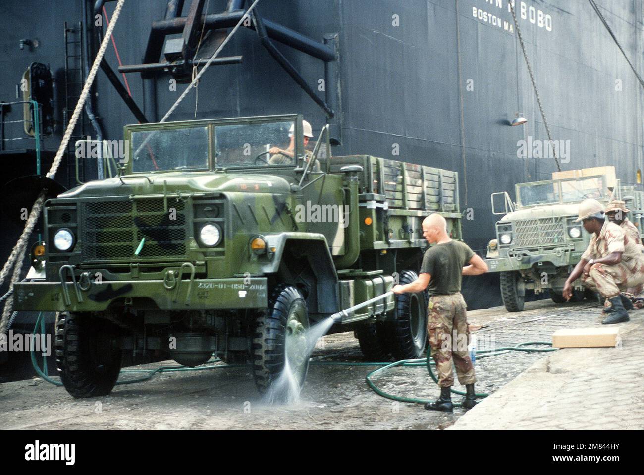 An M-939 5-ton cargo truck is washed off before being loaded aboard the ...