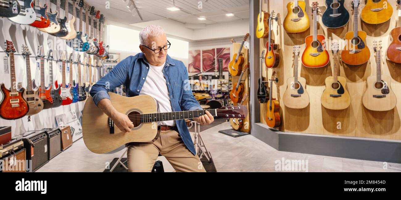 Mature man playing an acoustic guitar inside a music store Stock Photo ...