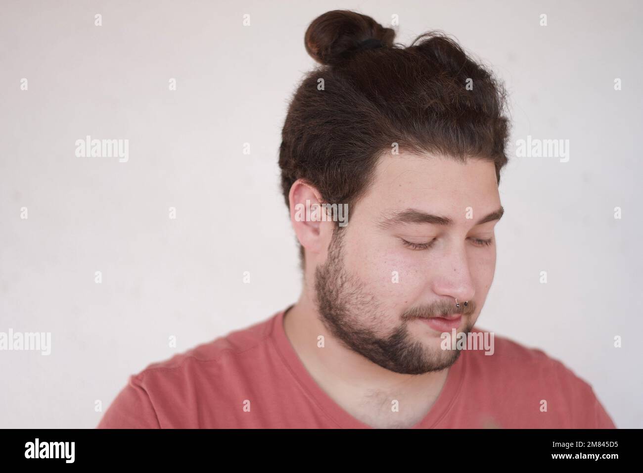 A closeup shot of a man with a ponytail hair looking away on the empty ...