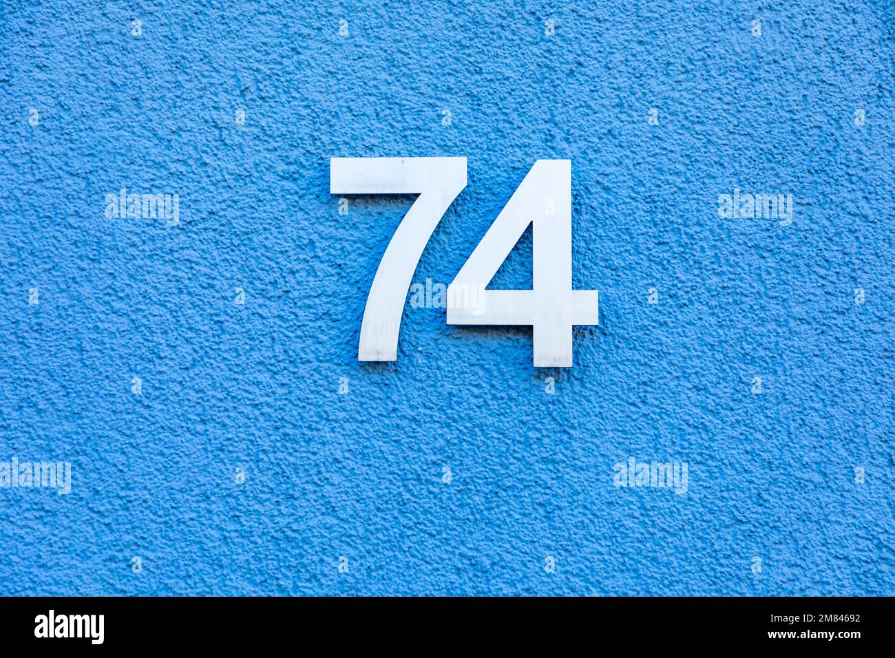 house number 74 wirth blue wall background in Germany Stock Photo - Alamy