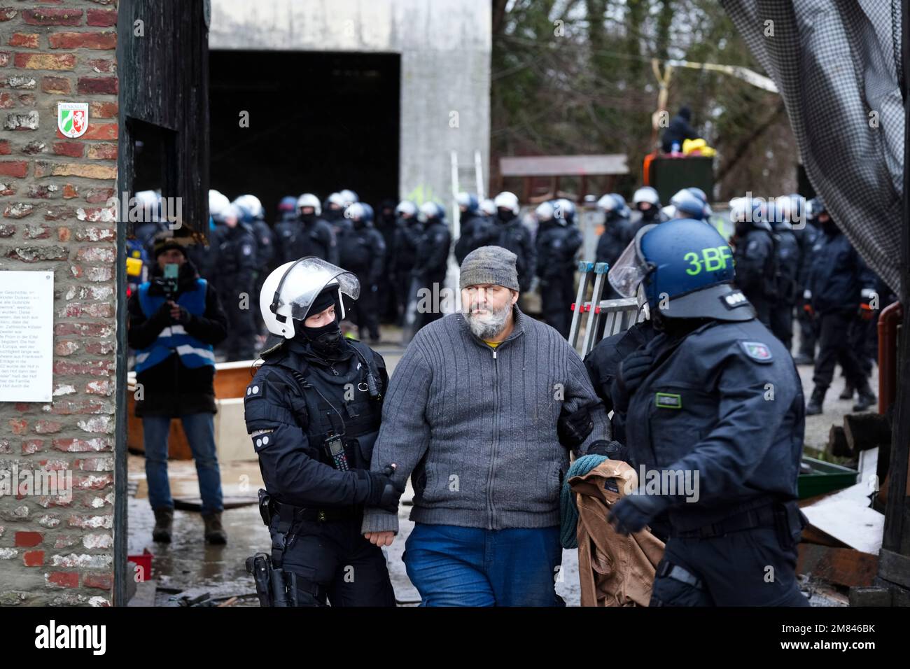 Police officers lead away a man at the village Luetzerath, near ...