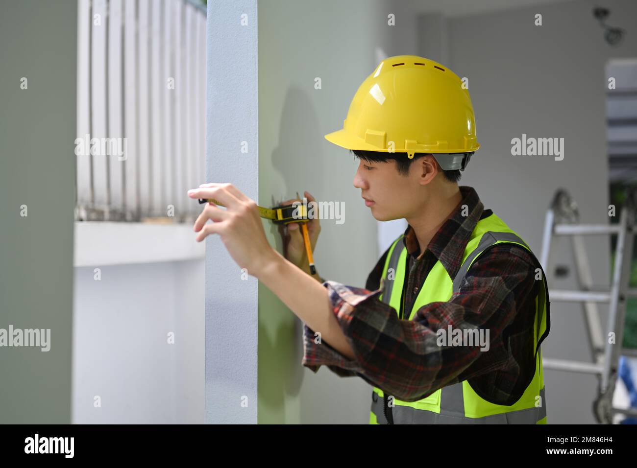 Asian male inspector wearing safety helmet and vest working building ...