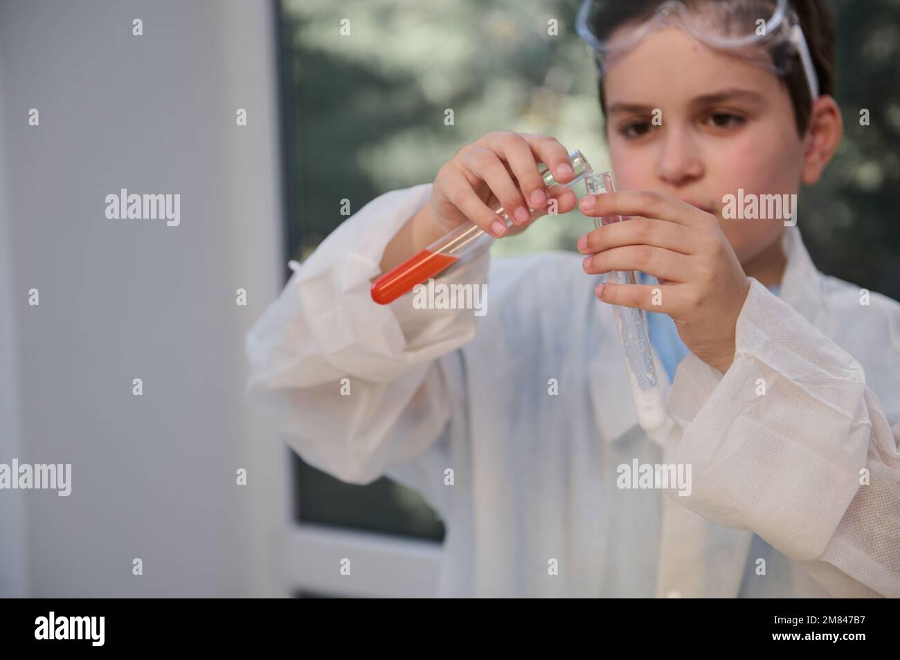 Closeup schoolboy's hands with test tubes with chemicals and reagents ...